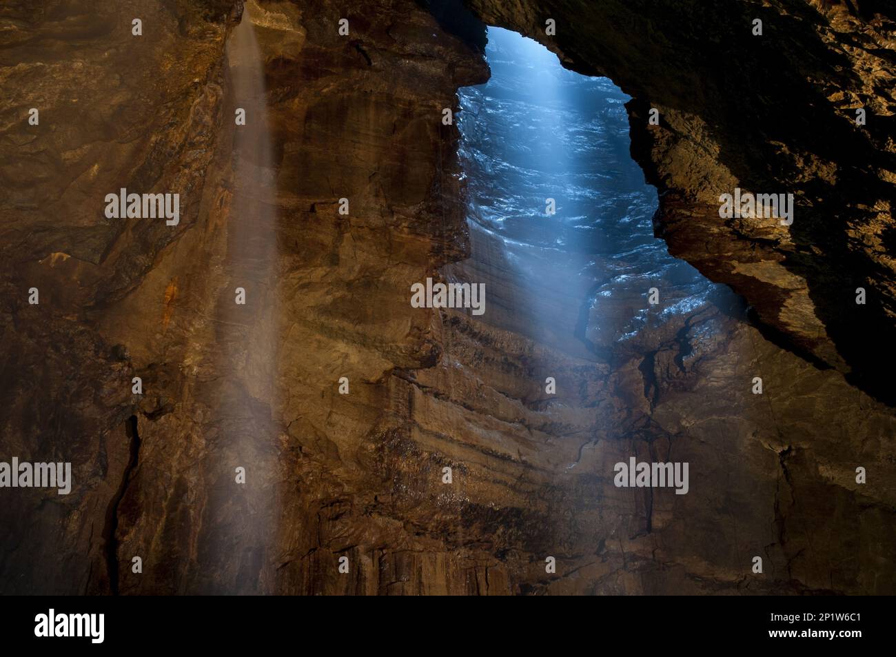 View of upland stream waterfall flowing down chasm into chamber of cave ...