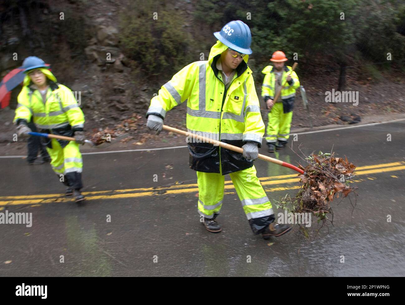 Workers with the California Conservation Corps clean debris from drains ...