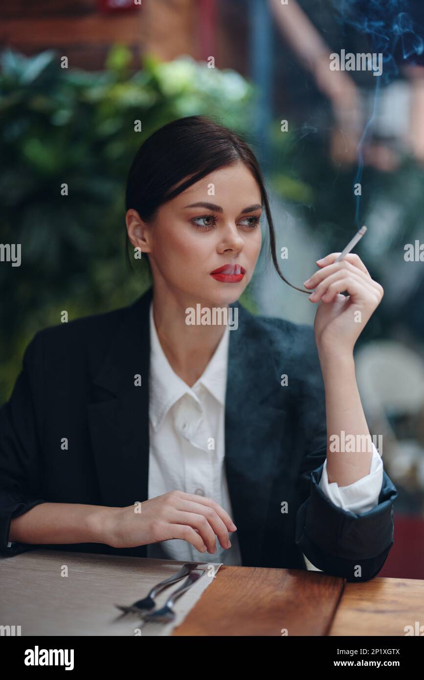 Stylish fashion woman portrait sitting in a cafe at a table and smoking ...