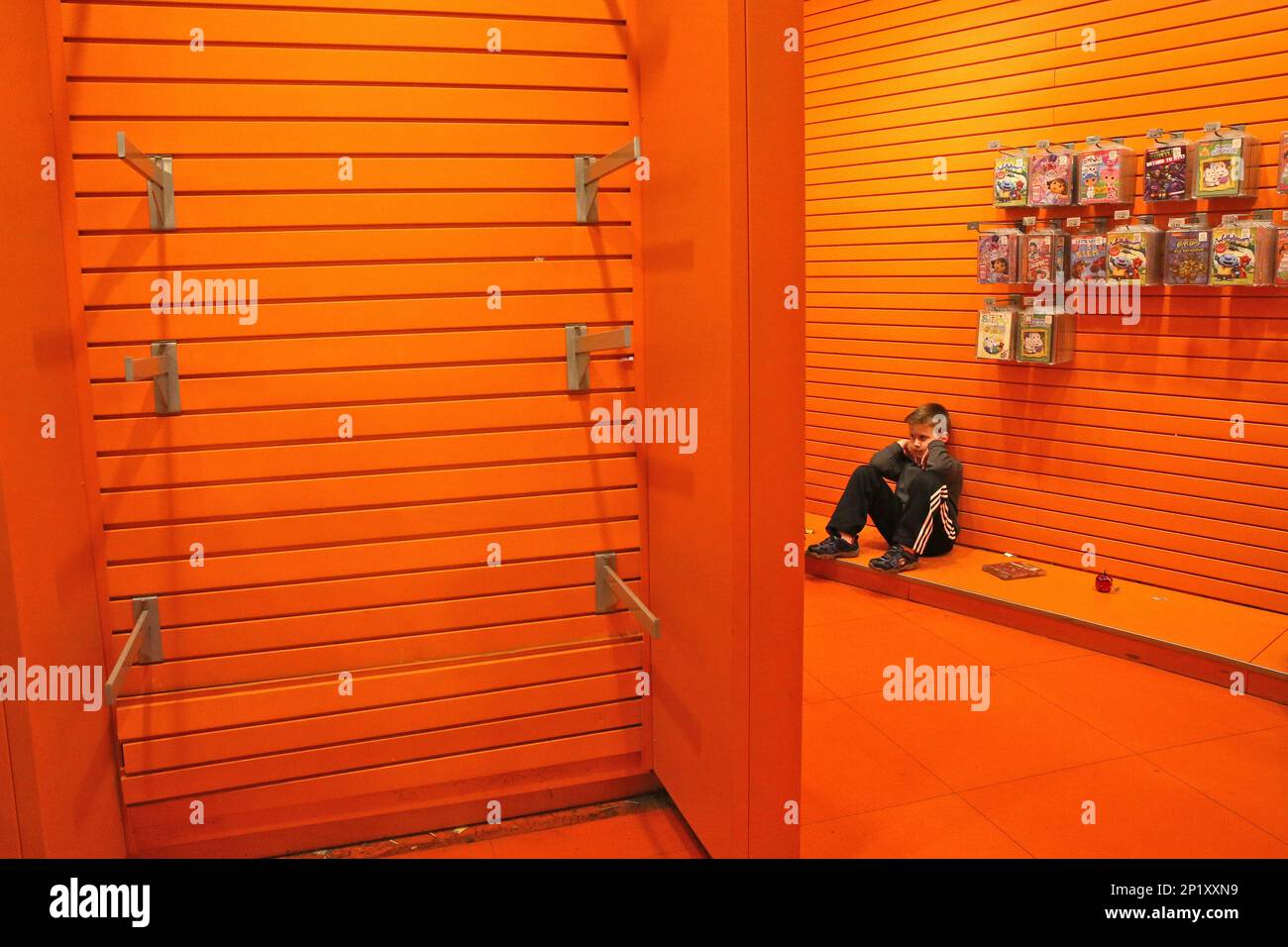 A child sits next to the empty toy displays at the Toys R Us store in ...
