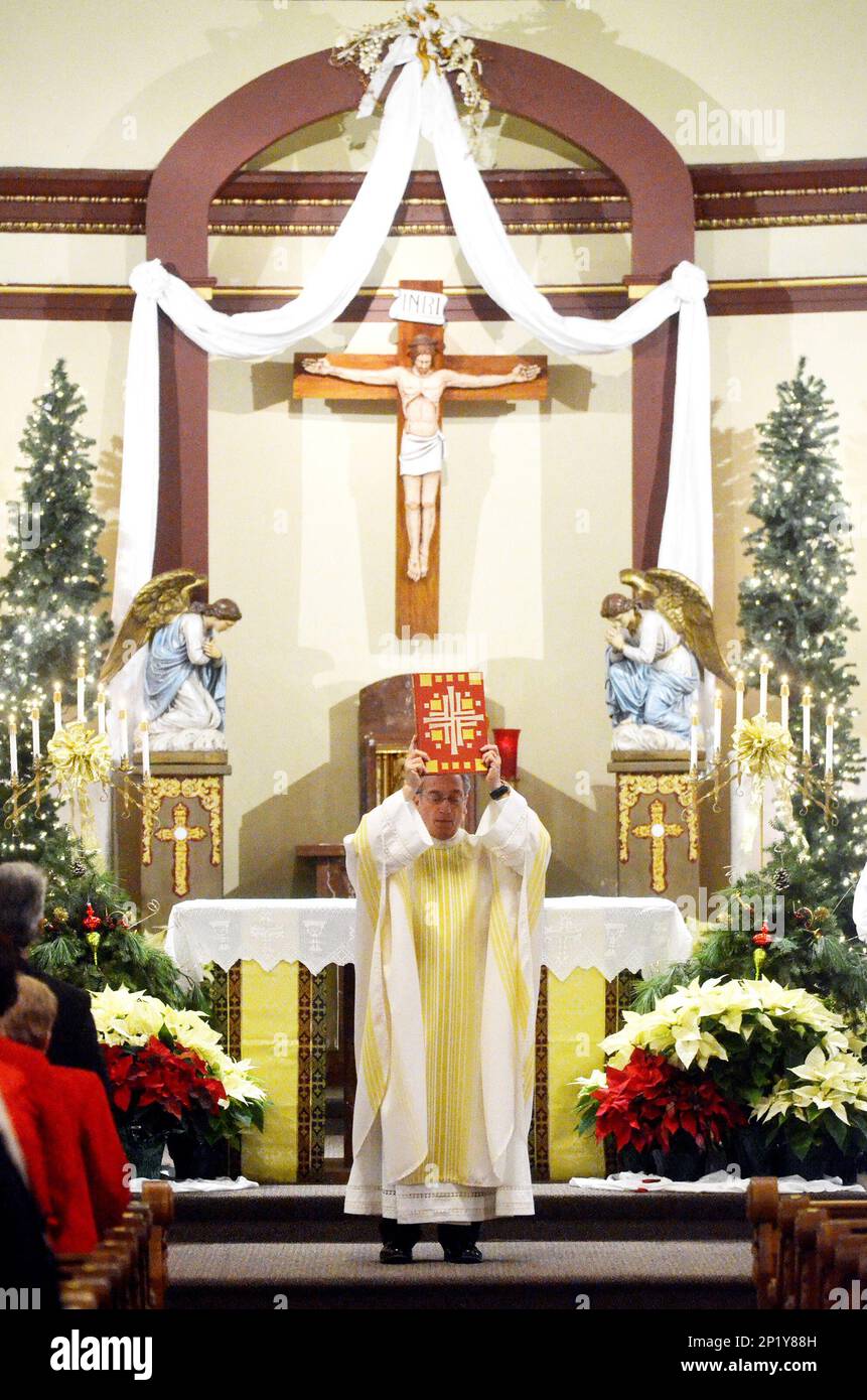 Father Raymond Thomas raises a Bible during a morning mass at Our Lady ...