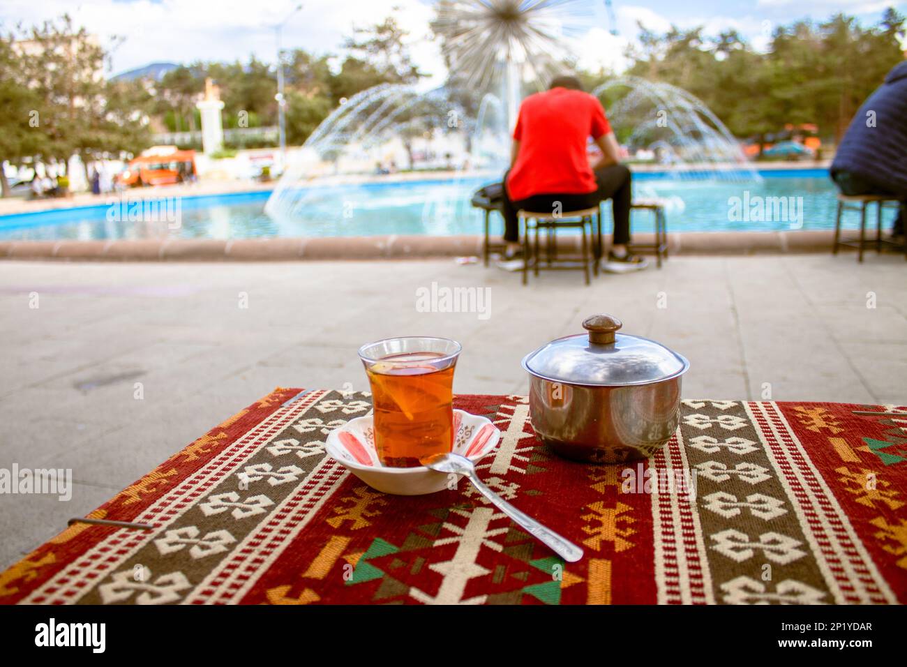 Cup of tea on a red-clad table and spending time in front of a pool ...