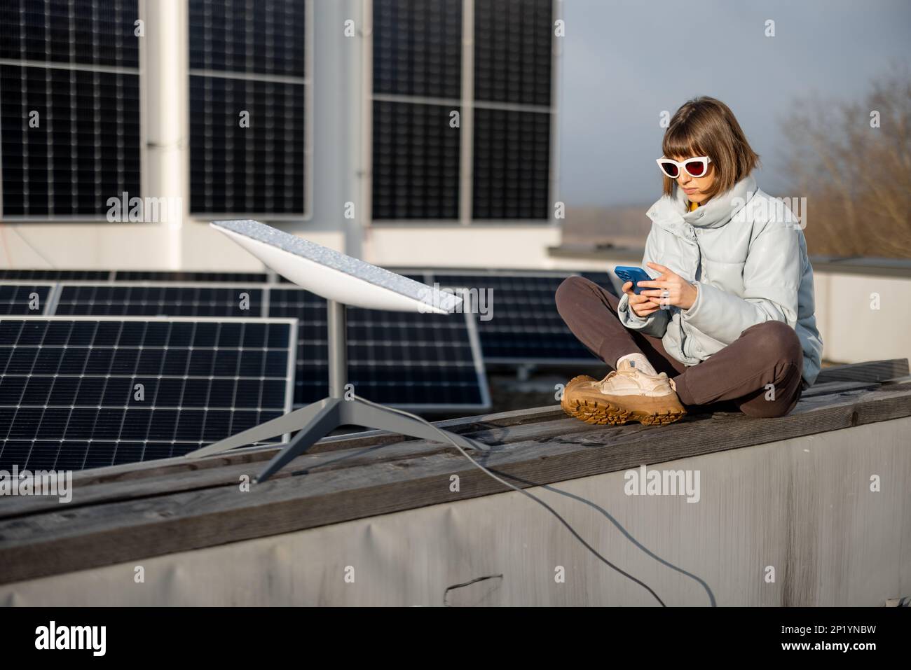 Woman uses Starlink Internet on roof with solar panels Stock Photo - Alamy
