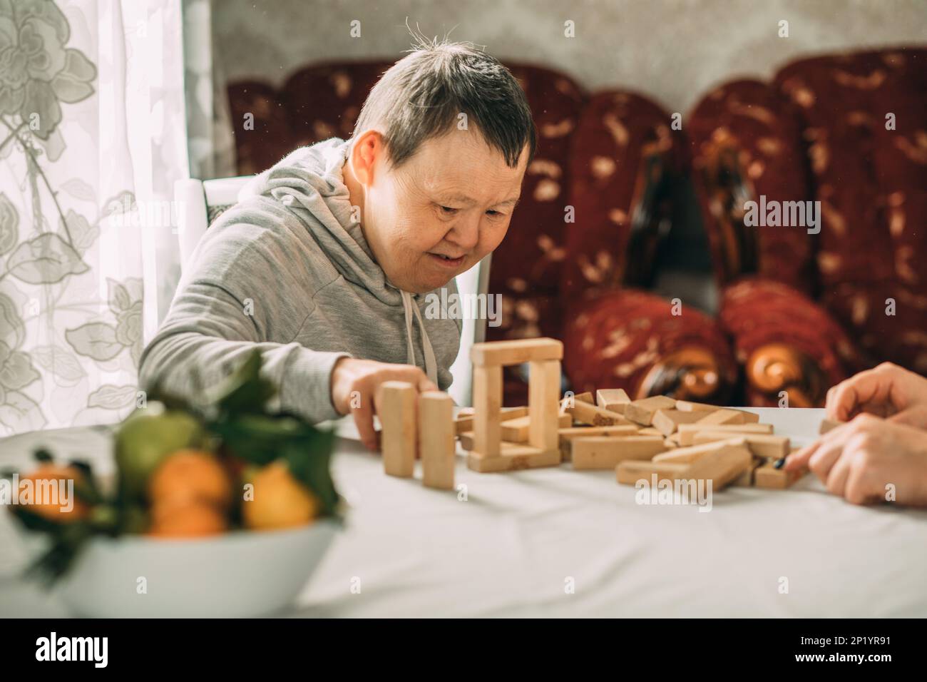 An elderly woman with down syndrome builds towers of their wooden toy ...
