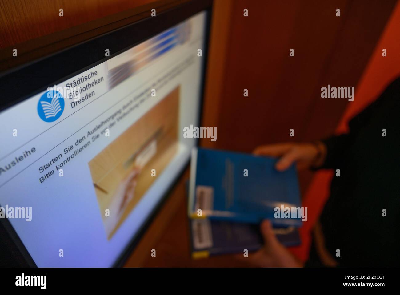Dresden, Germany. 27th Feb, 2023. A woman holds books for checkout over ...