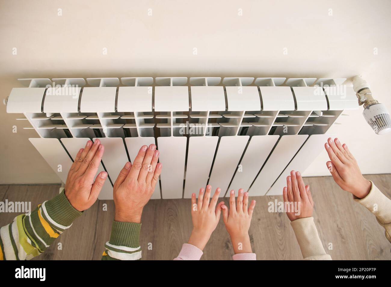 The family warms their hands near the radiator Stock Photo - Alamy