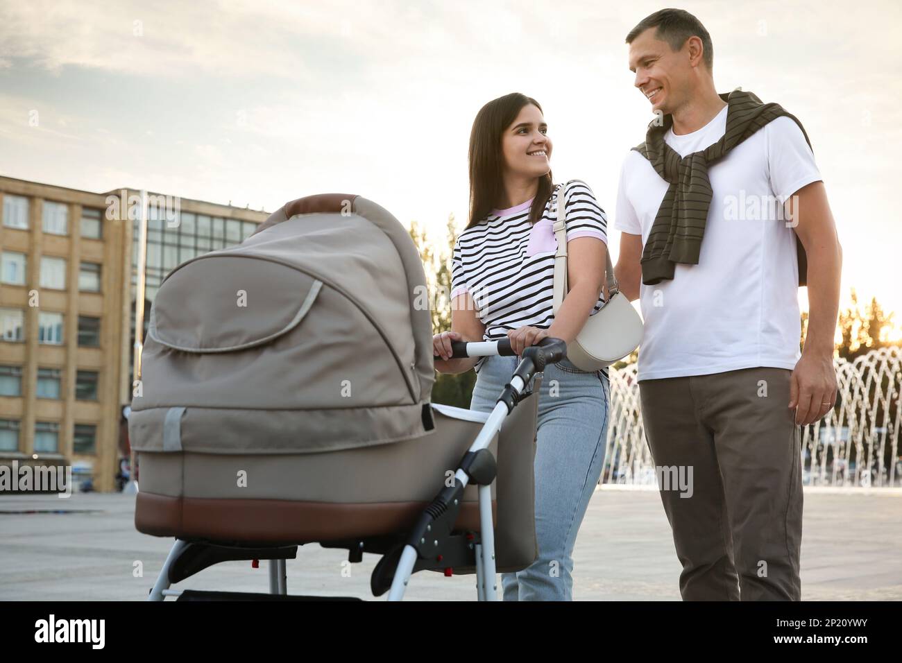 Happy parents walking with their baby in stroller outdoors Stock Photo ...