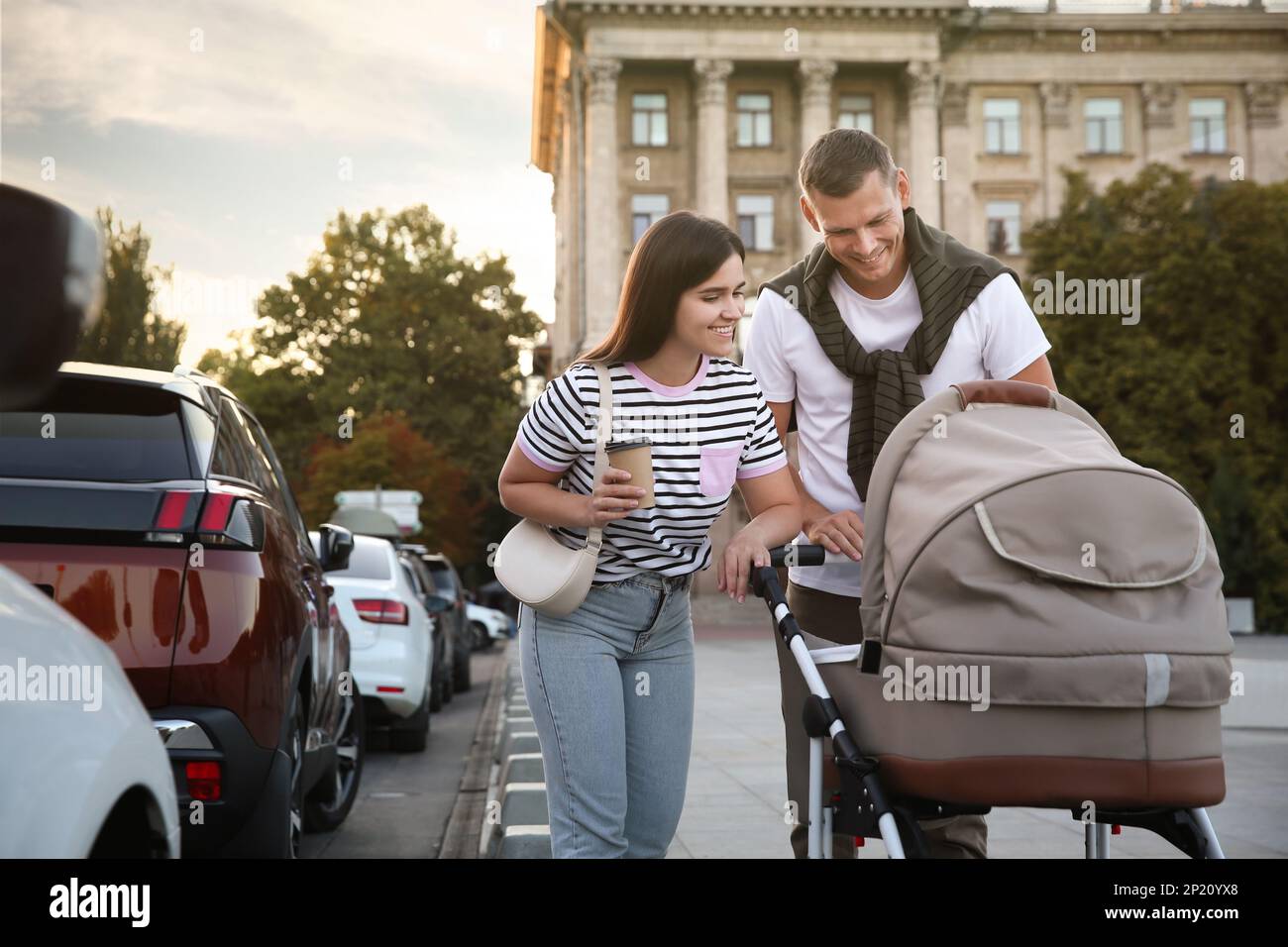 Happy parents walking with their baby in stroller outdoors Stock Photo ...