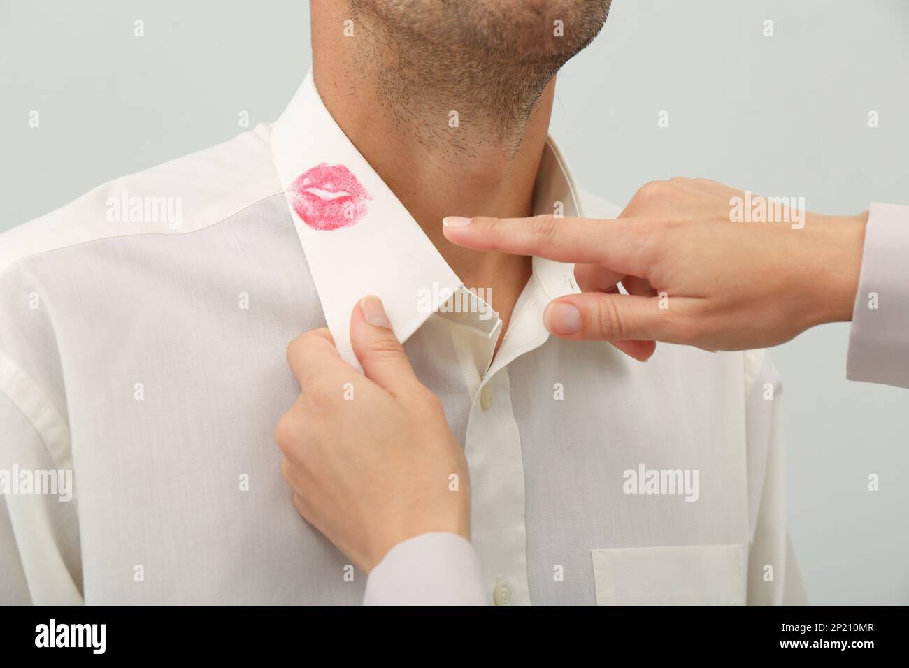 Woman pointing at lipstick kiss mark on her husband's shirt, closeup ...