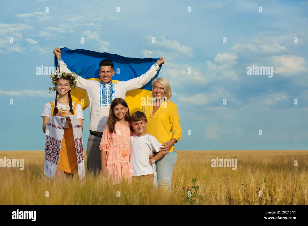 Happy family with national flag of Ukraine and treat in field. Space ...