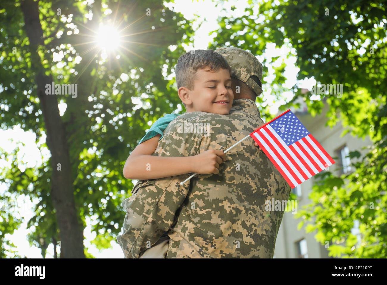 Soldier and his little son with flag of USA hugging outdoors Stock ...