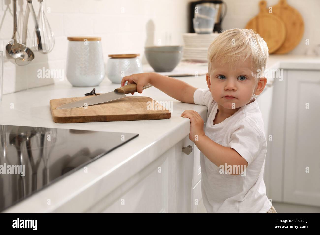 Curious little boy taking sharp knife from kitchen counter Stock Photo ...
