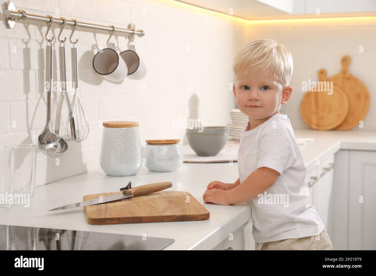 Curious little boy near kitchen counter with cutting board and sharp ...