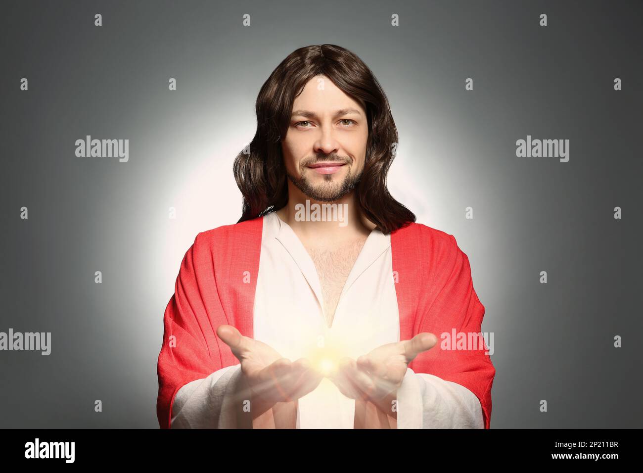 Jesus Christ on grey background. Miraculous light in hands Stock Photo ...