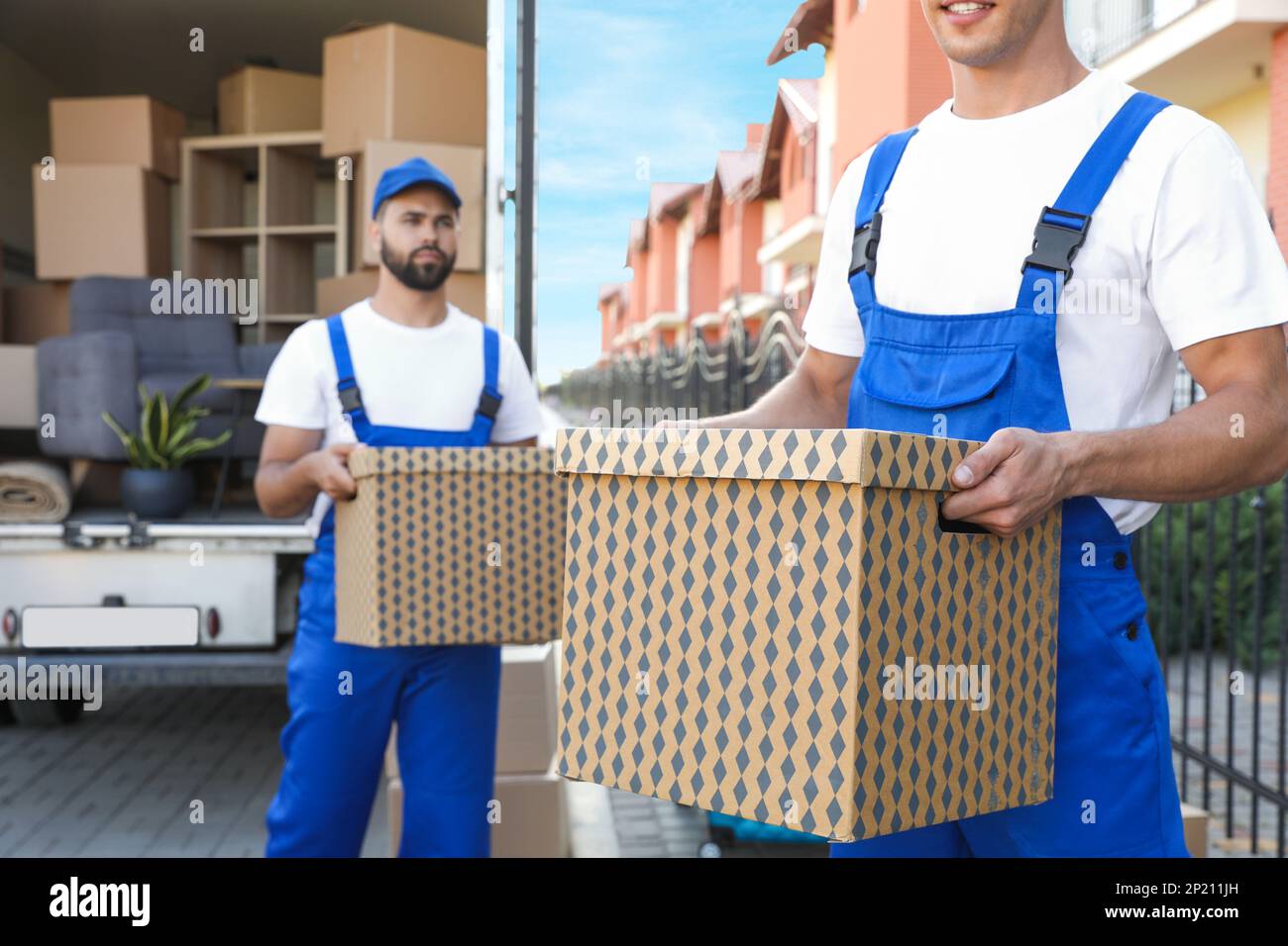 Workers unloading boxes from van outdoors. Moving service Stock Photo ...