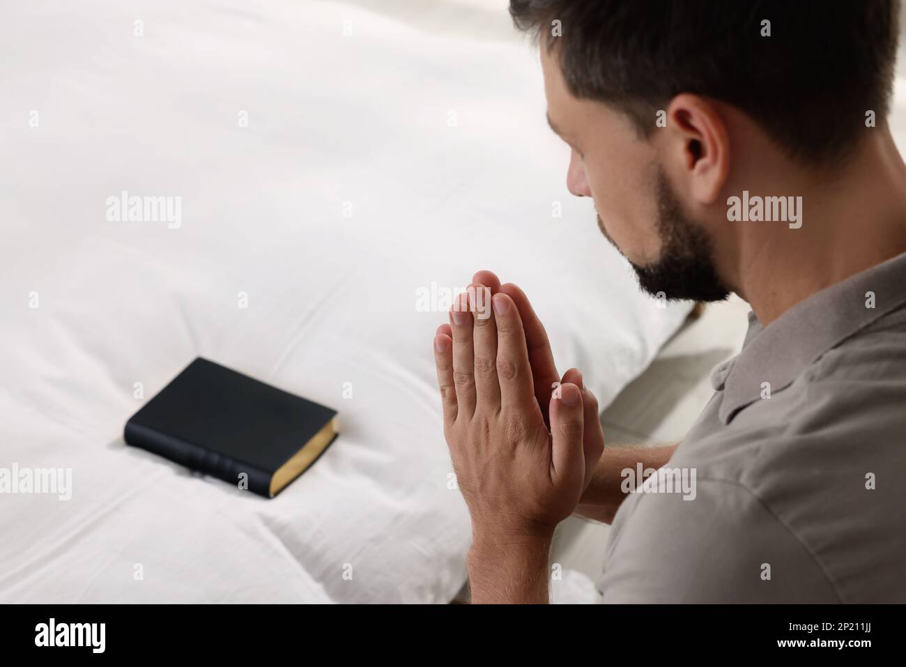 Religious man with Bible praying in bedroom, closeup Stock Photo - Alamy