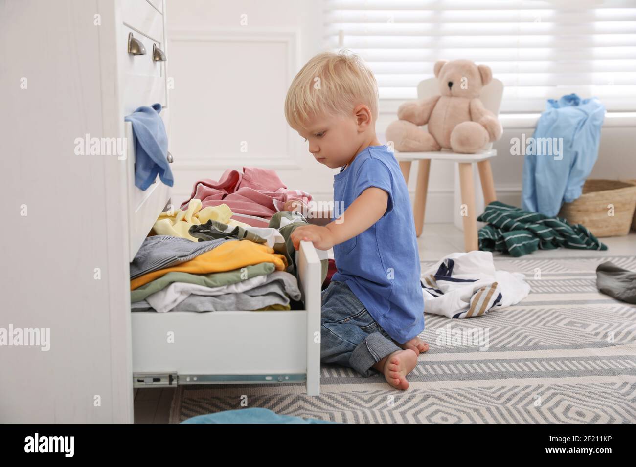 Cute little boy playing with clothes in dresser's drawer at home Stock ...