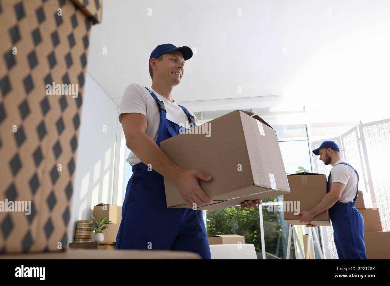 Moving service employees with cardboard boxes in room Stock Photo - Alamy