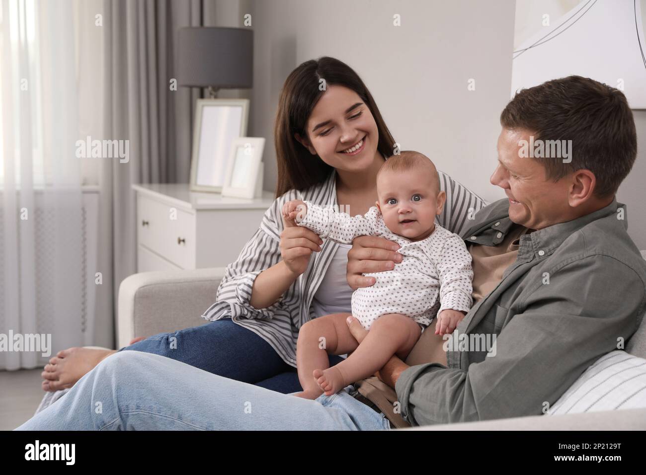 Happy family with their cute baby in living room at home Stock Photo ...