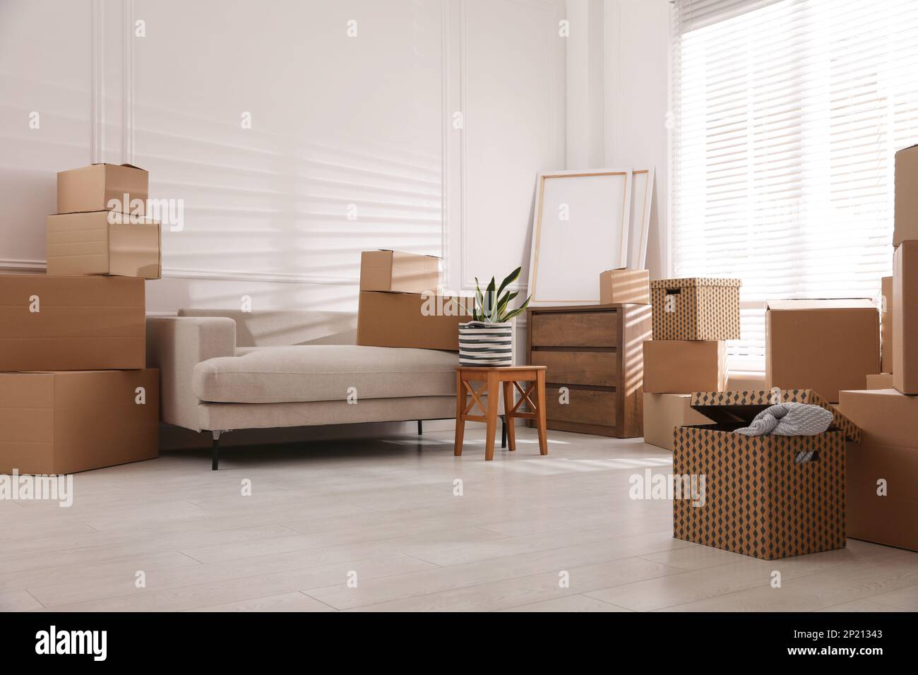 Furniture and cardboard boxes with packed stuff in room. Moving day ...