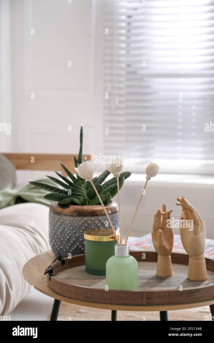 Wooden tray with air reed freshener, plant and mannequin hands on table ...