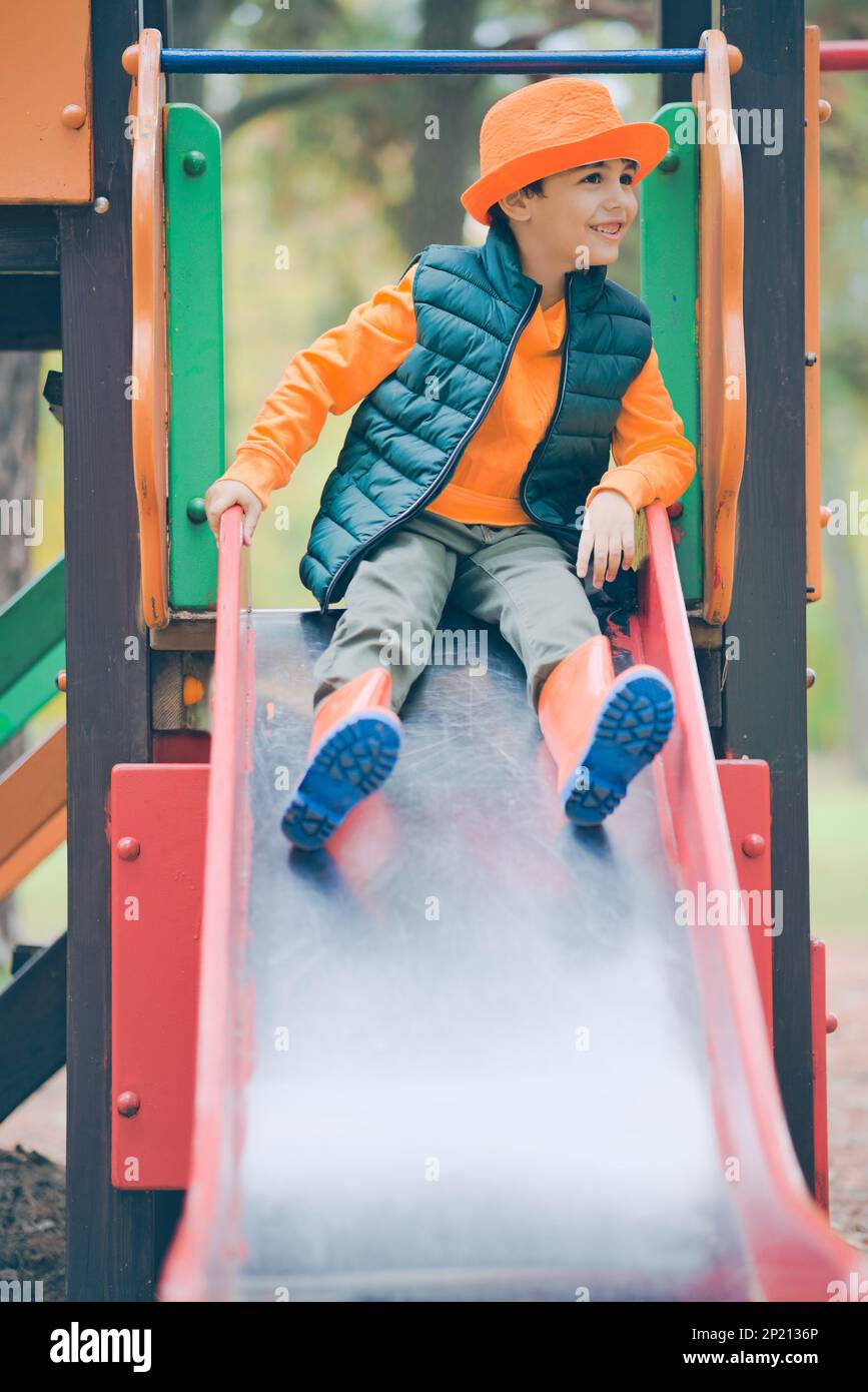 Happy little boy slides down the slide at the children's playground ...