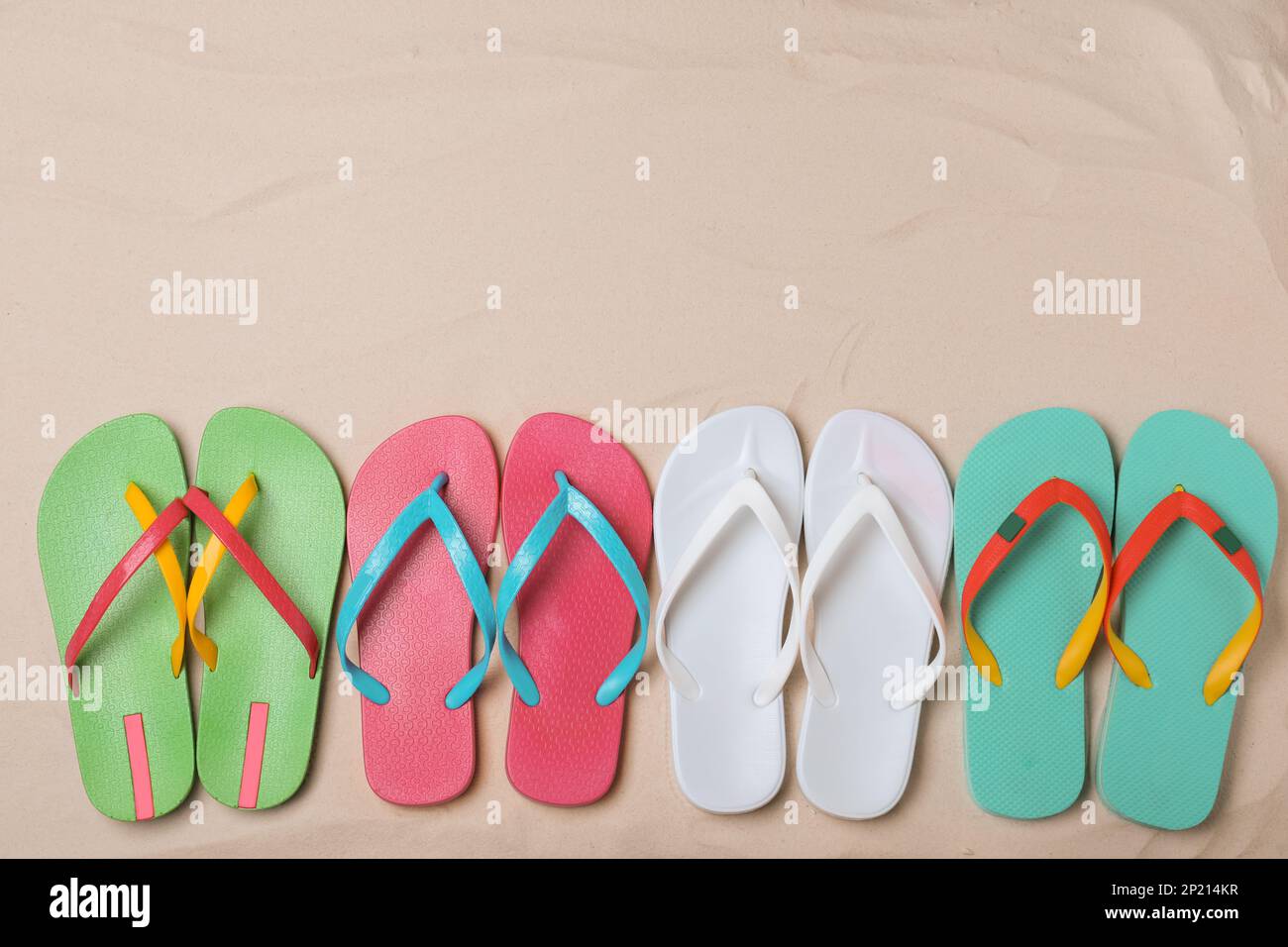 Different bright flip flops on sand, flat lay. Space for text Stock ...
