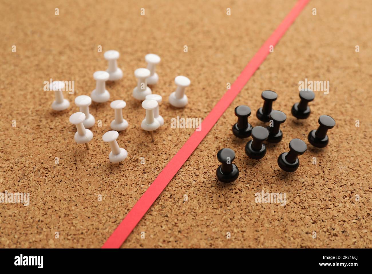Black and white push pins divided by red strip in cork board. Racism ...