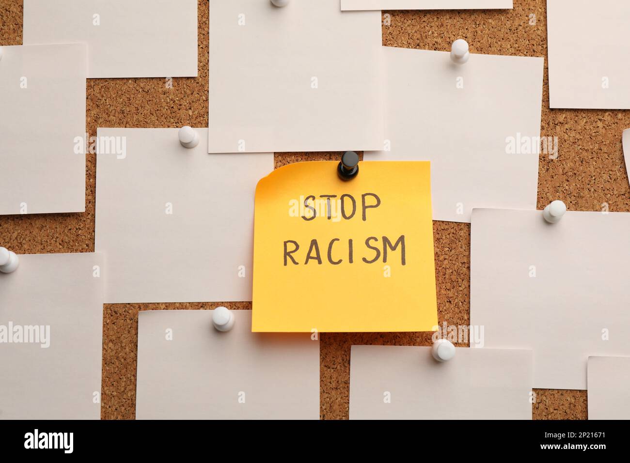 Yellow paper note with phrase Stop Racism among white ones attached to ...