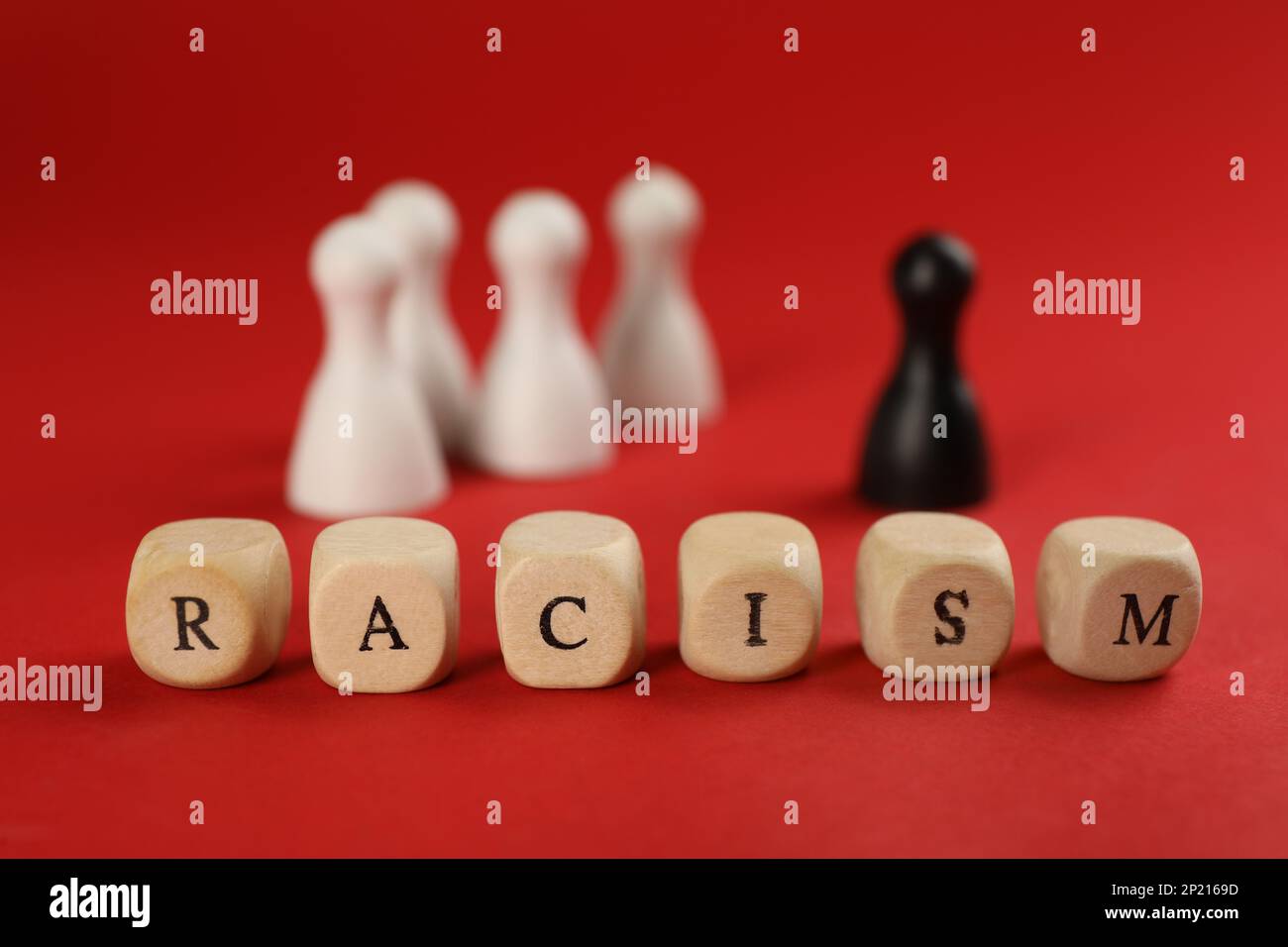 Word Racism made of wooden cubes with letters and black pawn among ...