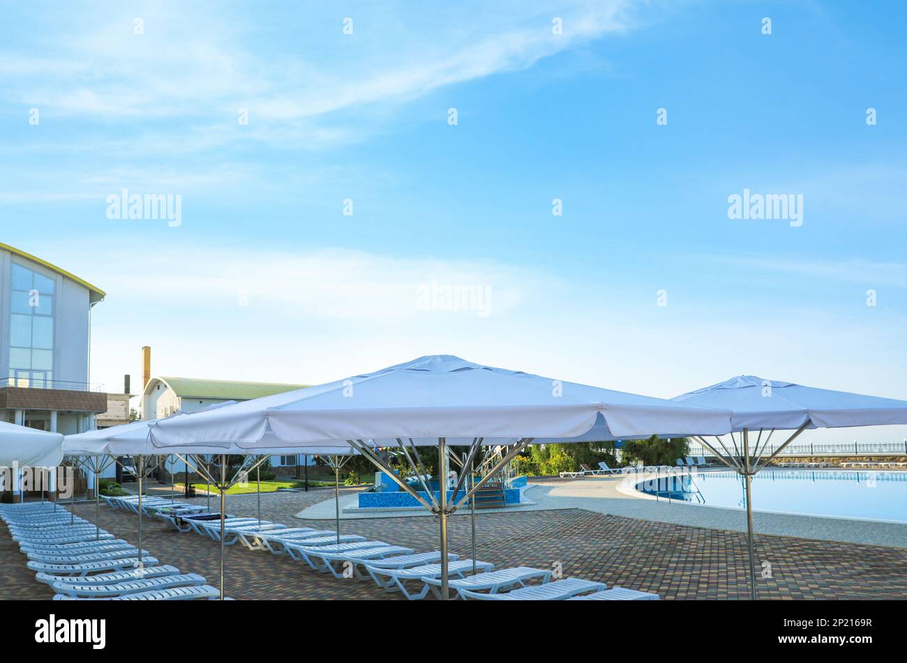 Beach umbrellas and sunbeds near outdoor swimming pool at resort Stock ...