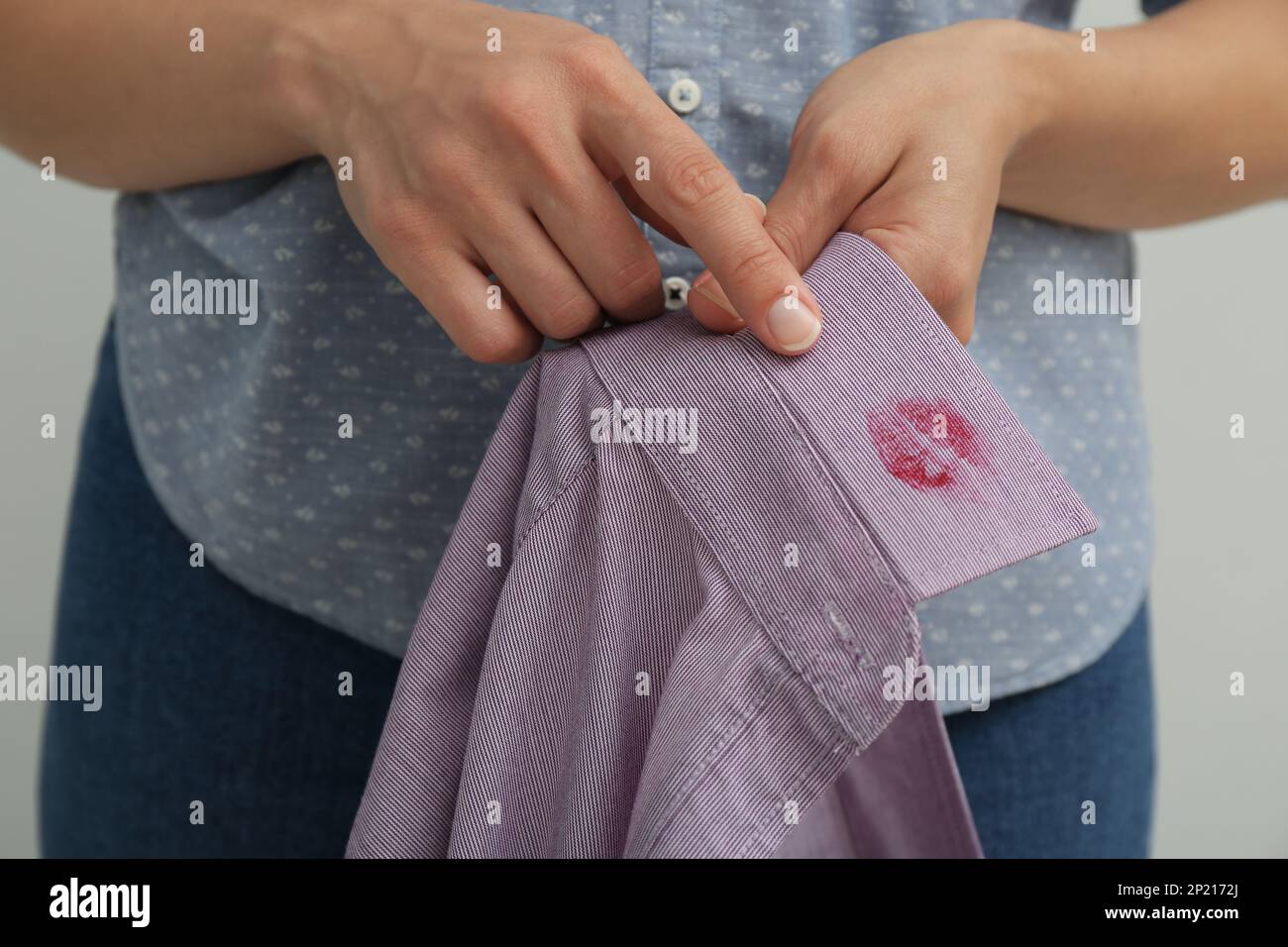Woman pointing at lipstick kiss mark on her husband's shirt, closeup ...