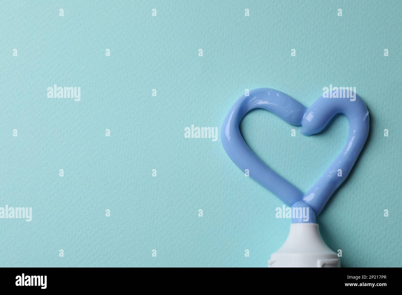 Heart made with toothpaste and tube on light blue background, flat lay ...