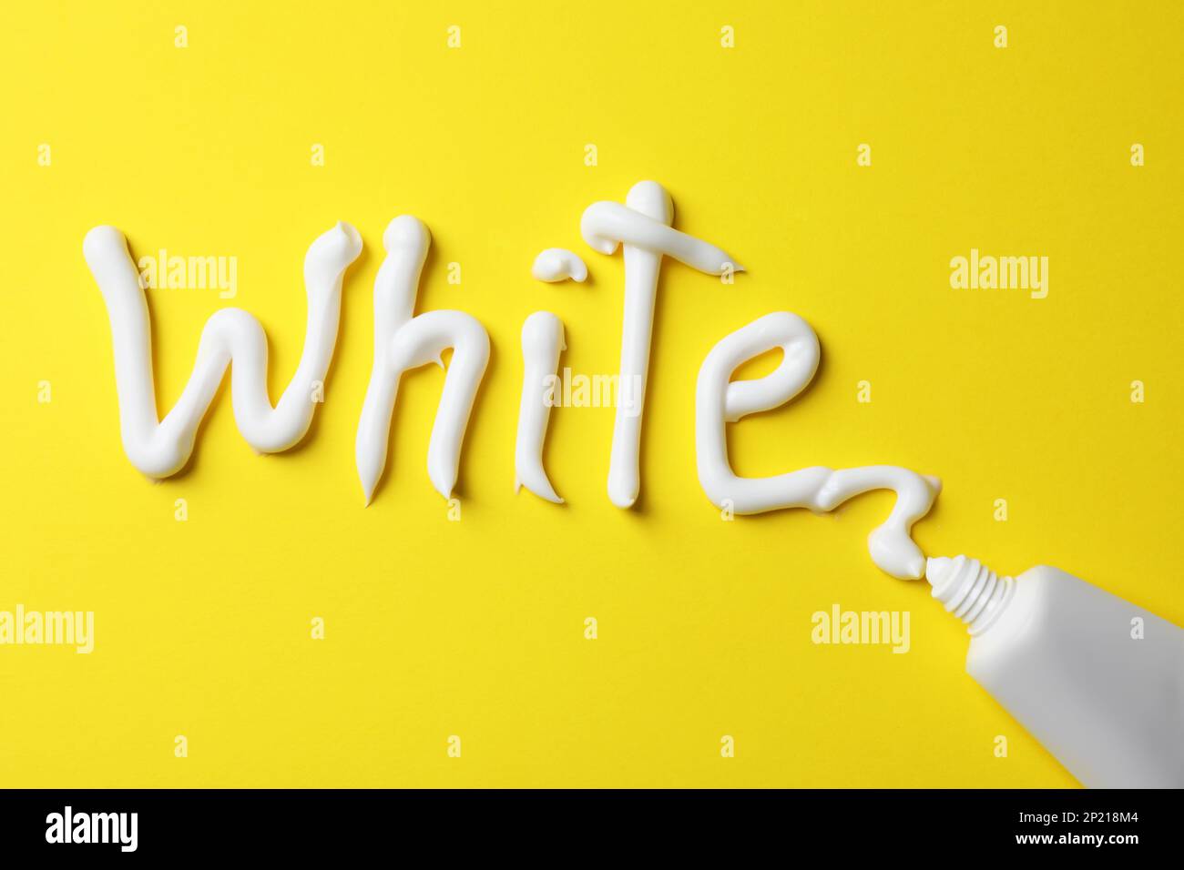 Word White written with toothpaste and tube on yellow background, top ...