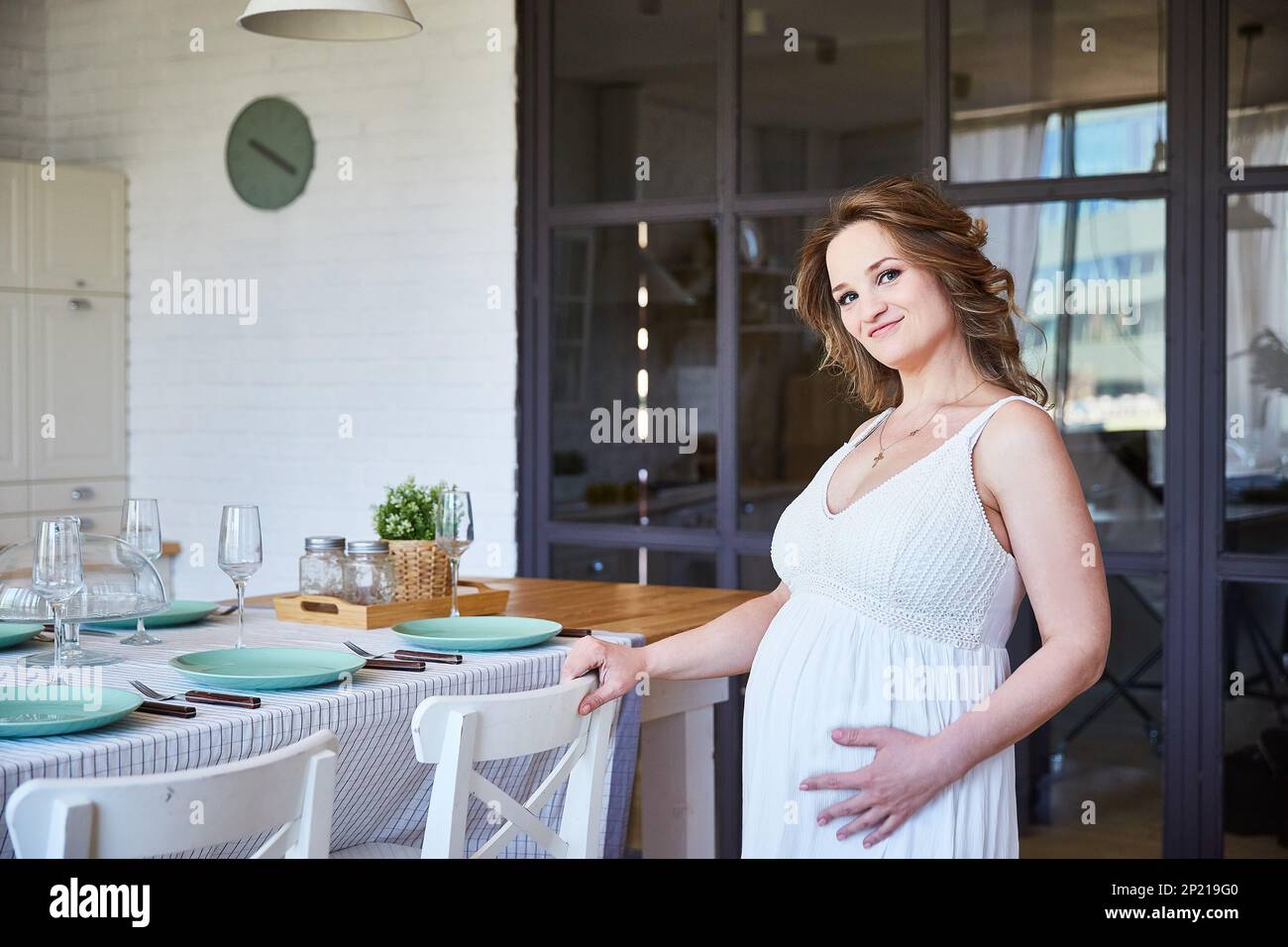 Pregnant woman with a belly set the table for the reception of guests ...