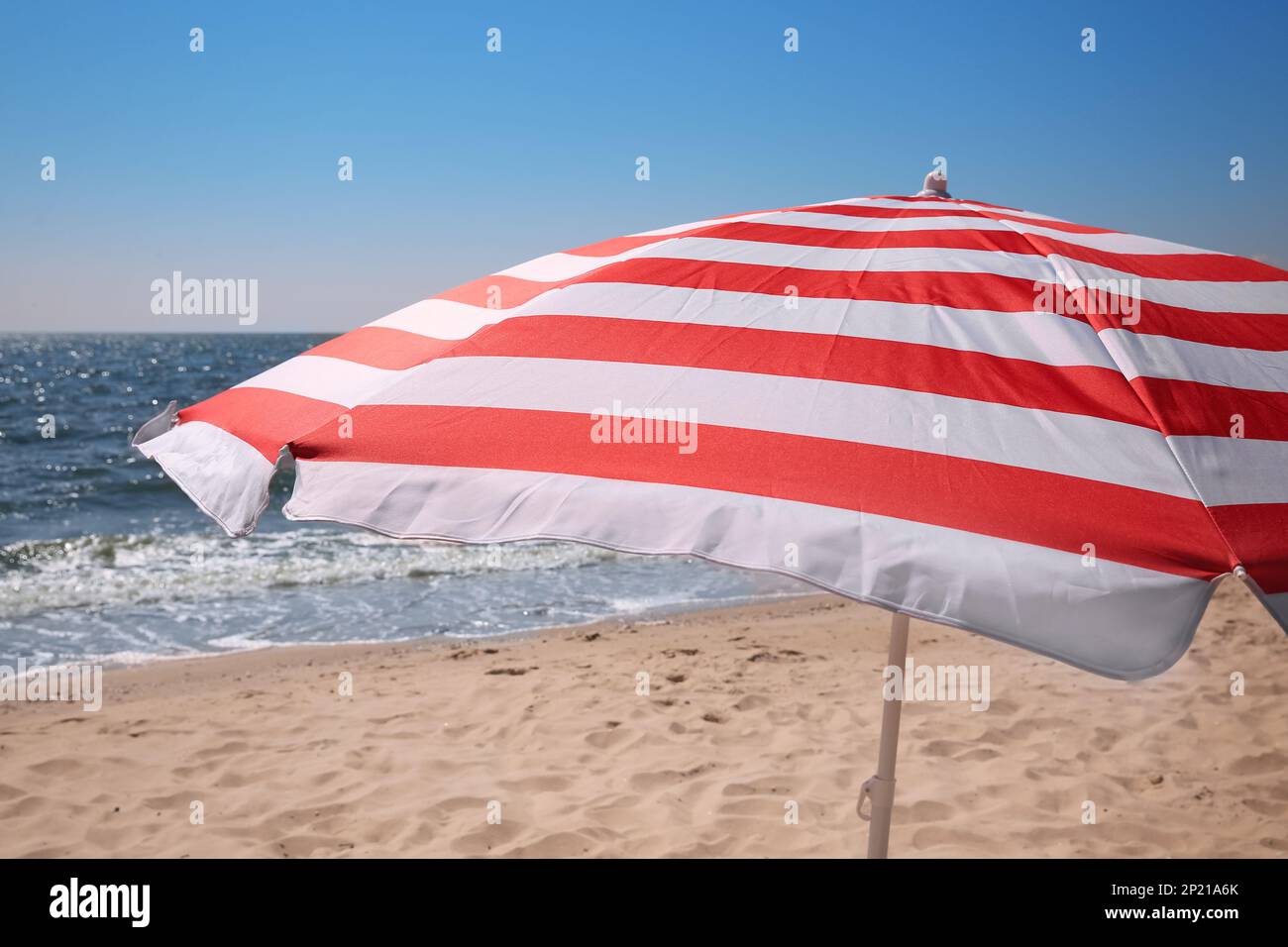 Red and white striped beach umbrella on sandy seashore Stock Photo - Alamy