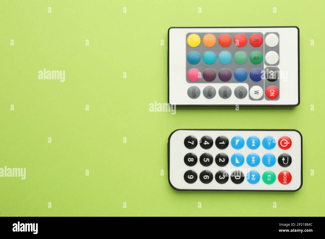 Remote controls on light green background, flat lay. Space for text ...