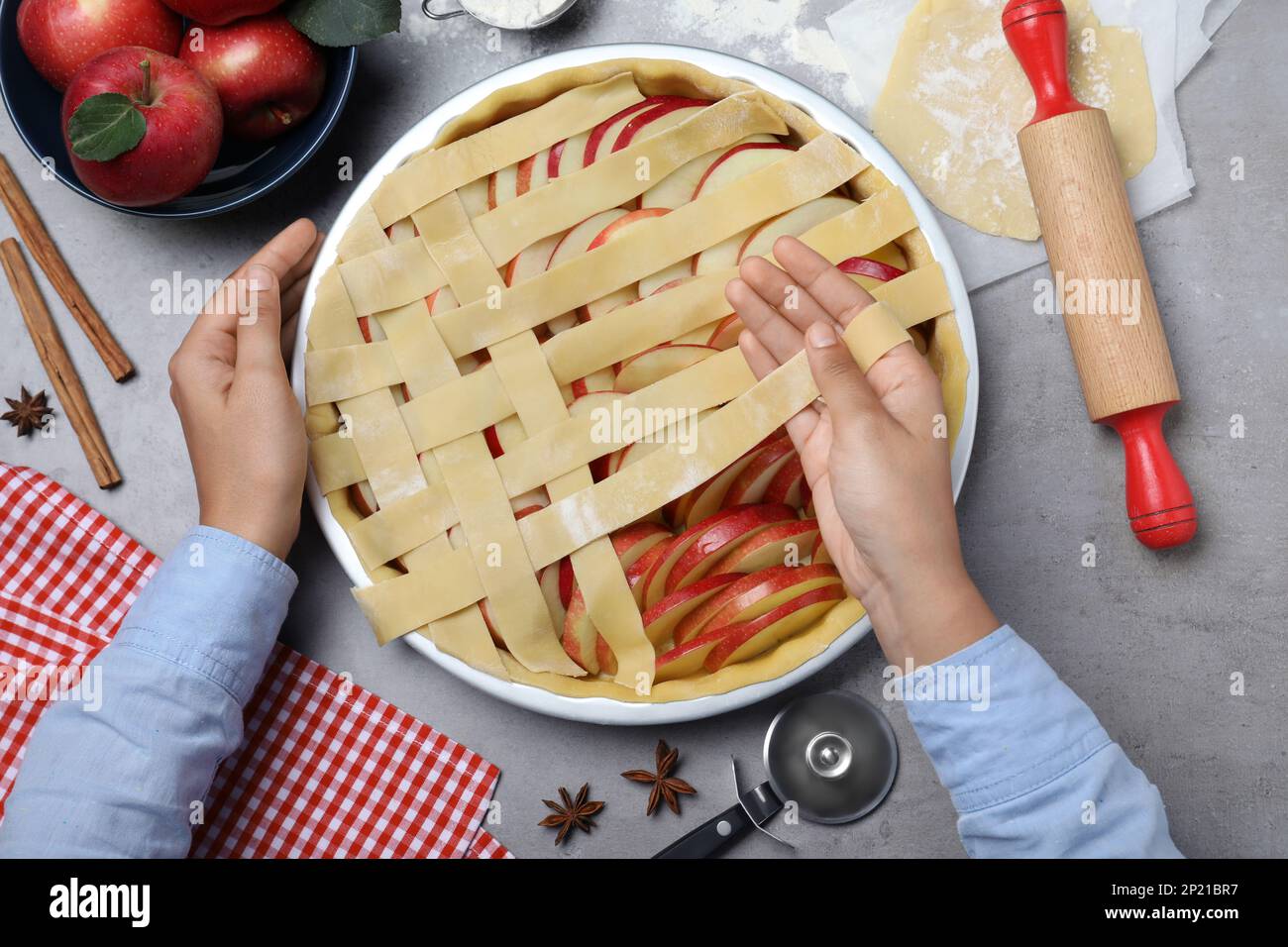 Woman decorating raw apple pie at grey table, top view Stock Photo - Alamy