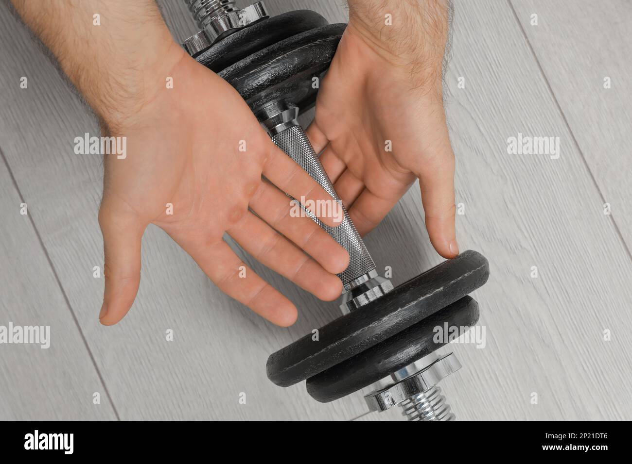Sporty man taking dumbbell indoors, closeup. Suffering from calluses on ...