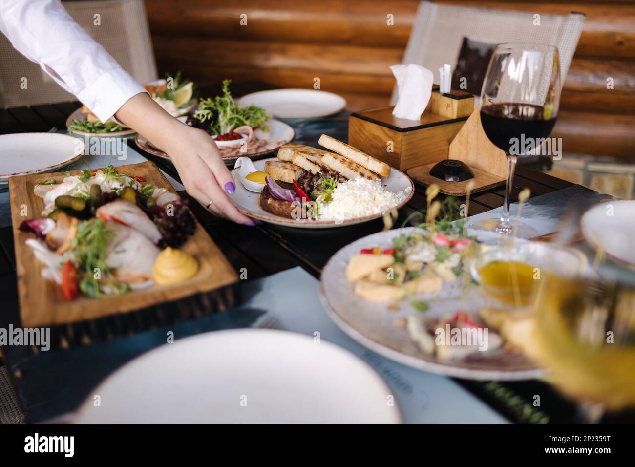 The waiter puts a plate with a snack on a table with food ...
