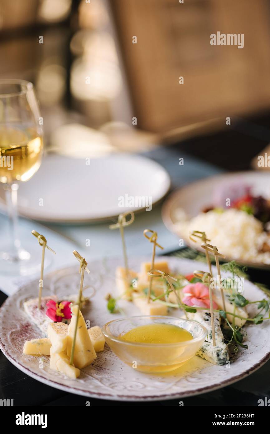 Four types of different cheeses sliced and served on a plate with honey ...