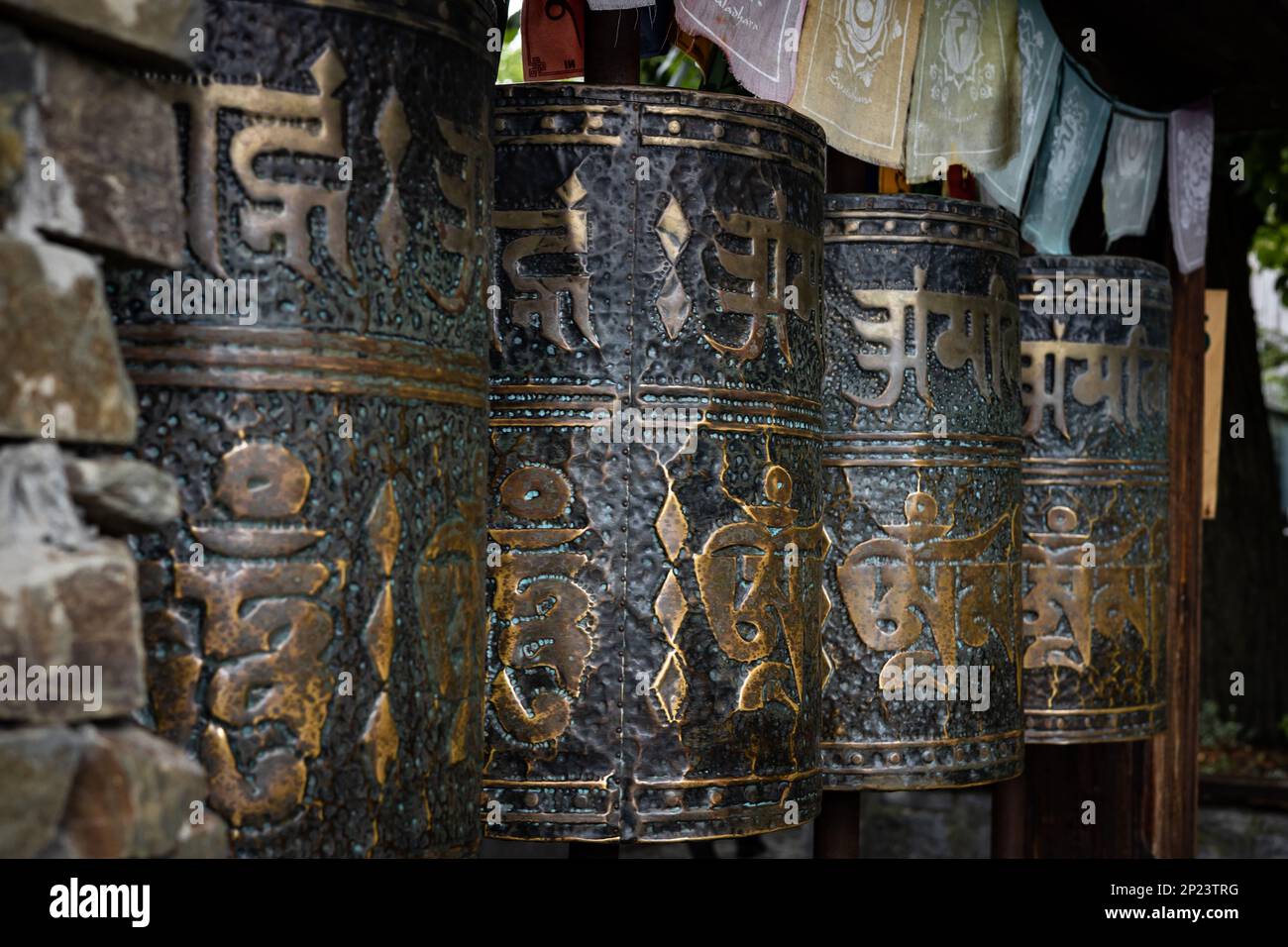 A row of metal tibetan buddhist prayer wheels with golden matra letters ...