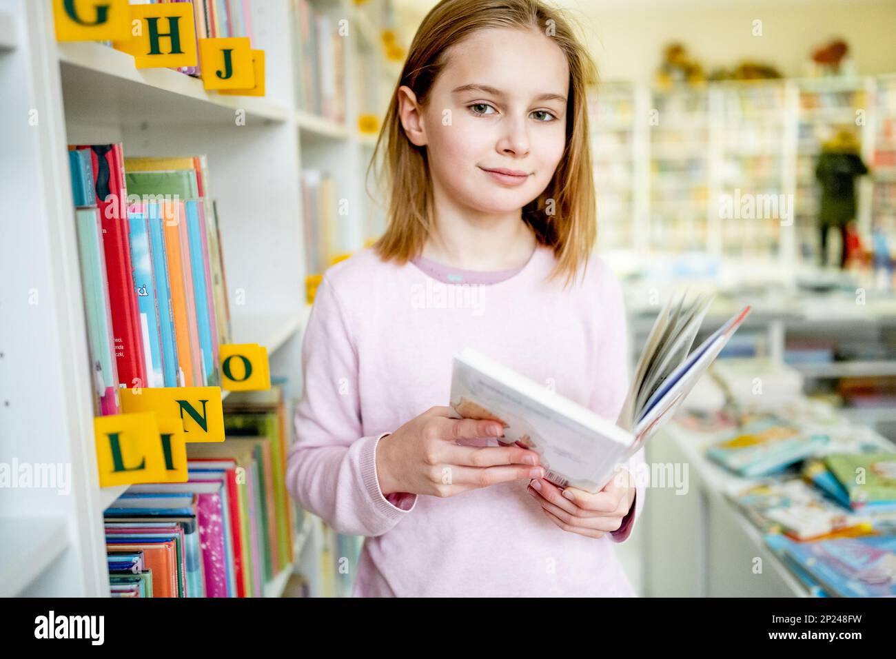 Schoolgirl choosing book in school library Stock Photo - Alamy