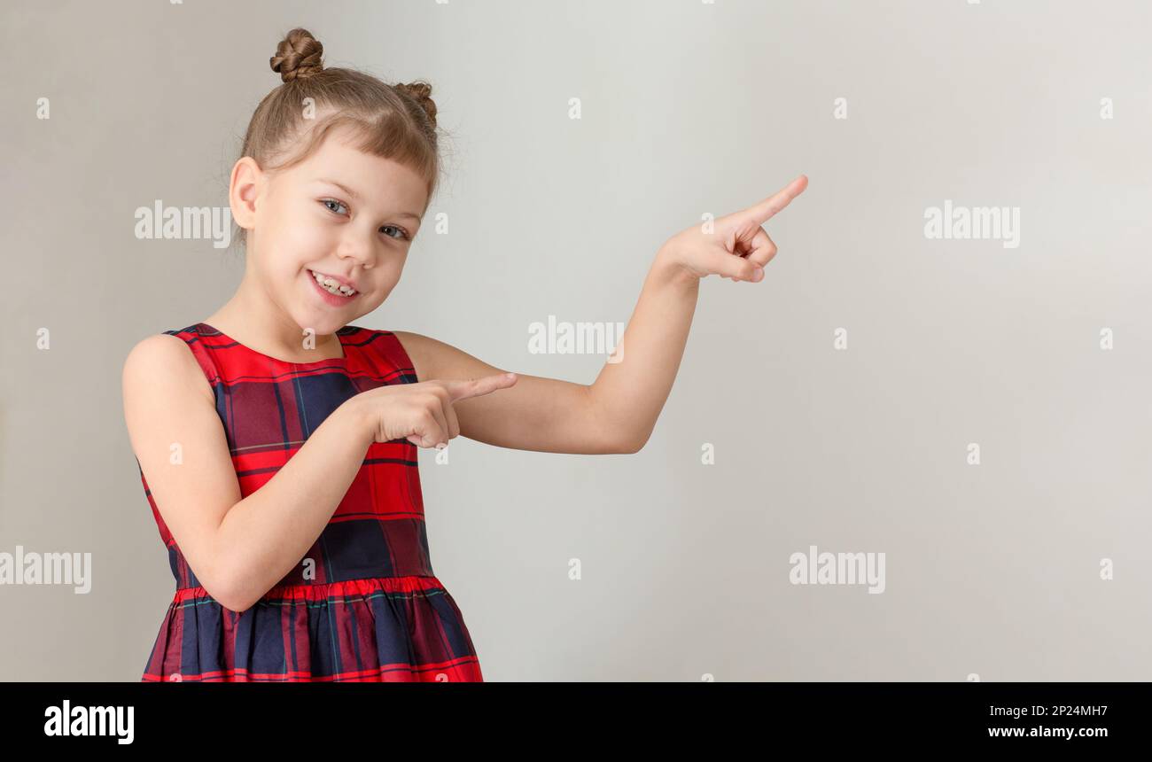 Smiling child showing on copy space by index finger on both hands ...