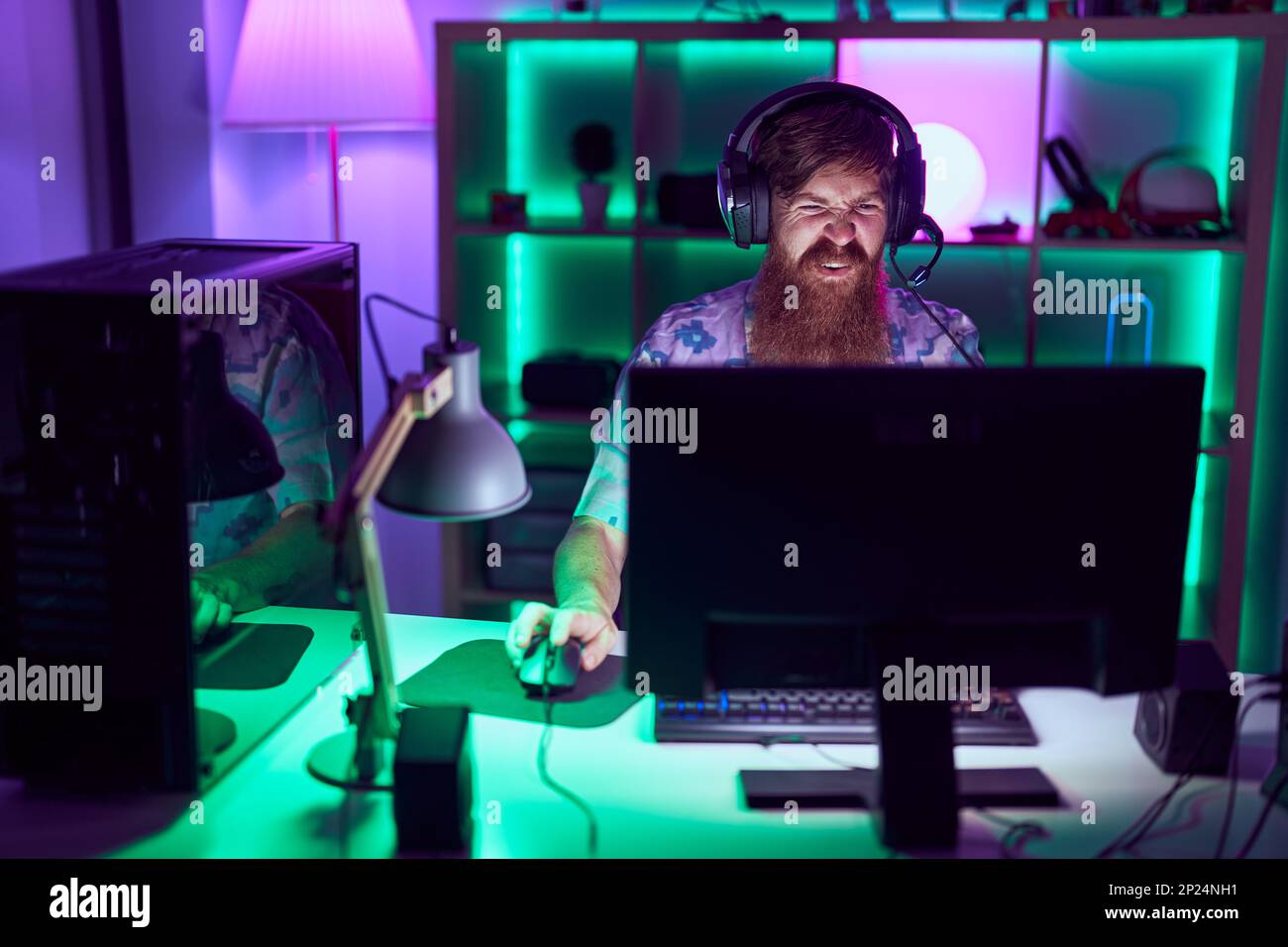 Young redhead man streamer playing video game using computer at gaming ...