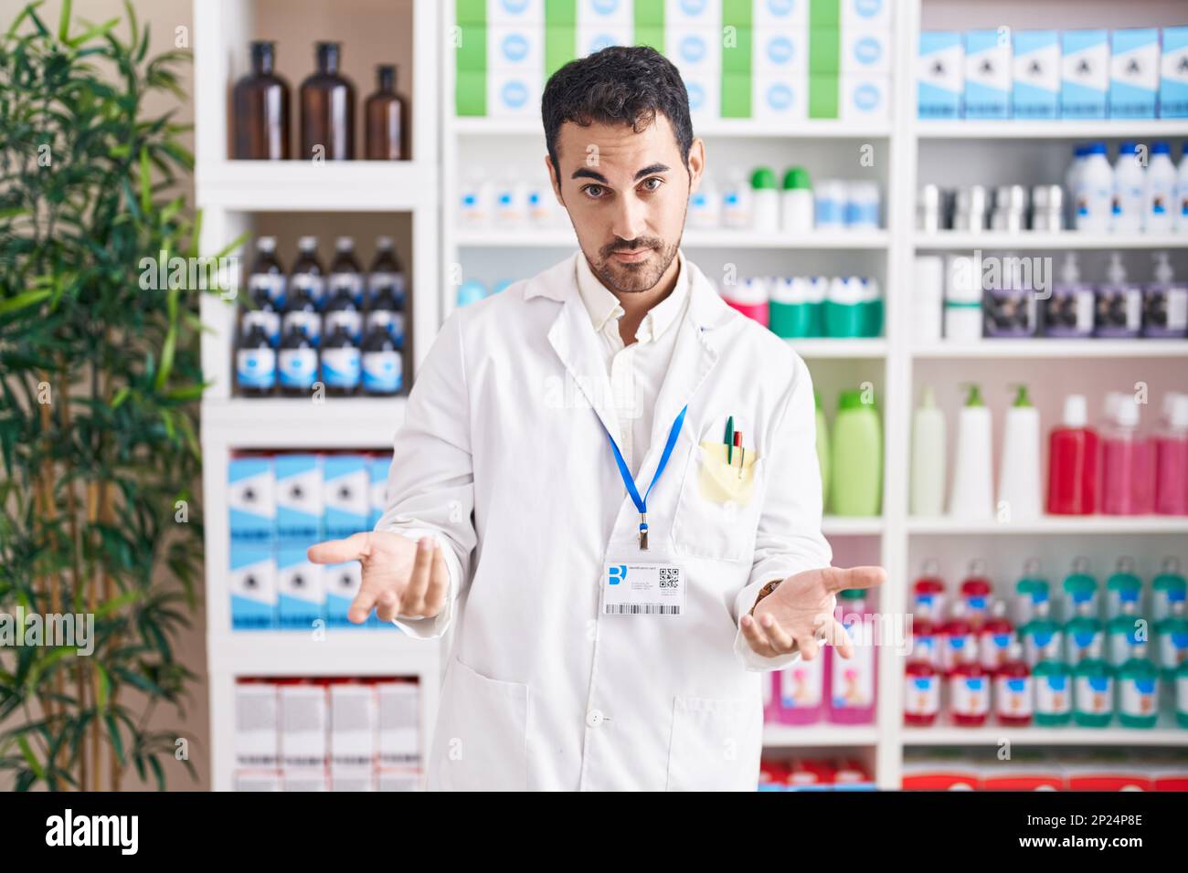 Handsome hispanic man working at pharmacy drugstore clueless and ...