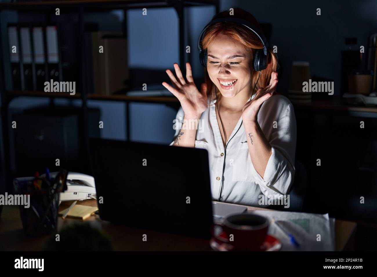 Young caucasian woman working at the office at night celebrating mad ...