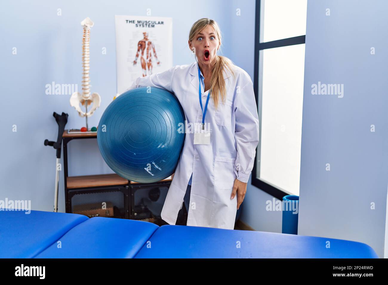 Beautiful woman holding pilates ball at physiotherapy clinic scared and ...
