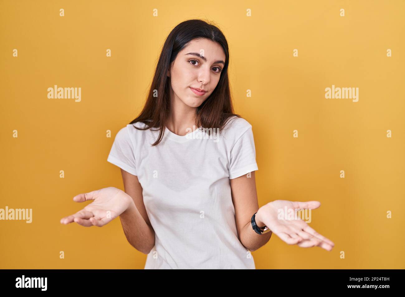Young beautiful woman standing over yellow background clueless and ...