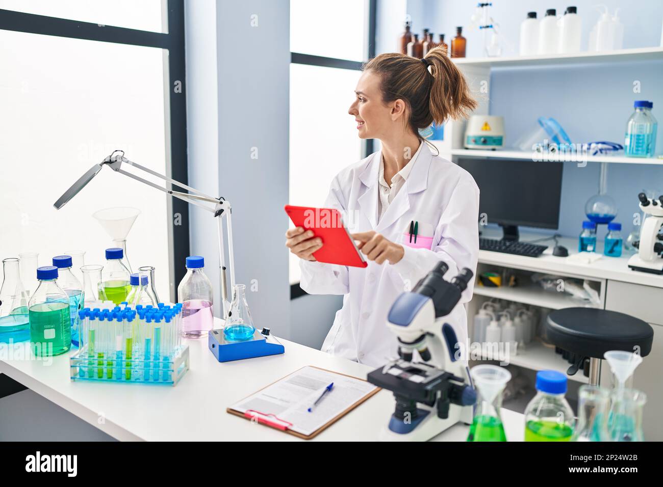 Young woman wearing scientist uniform using touchpad at laboratory Stock Photo - Alamy